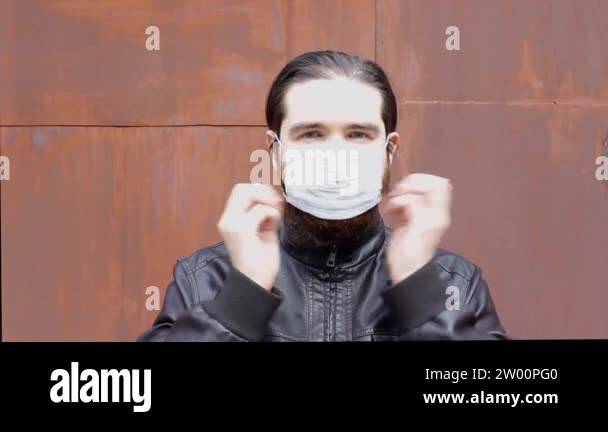 man puts on and removes a disposable mask to protect against the ...
