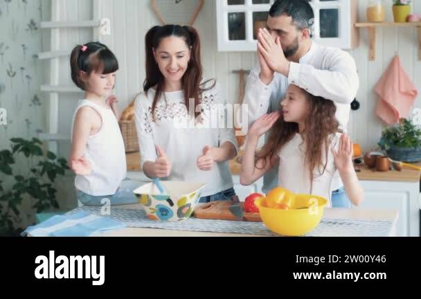 Parents and two daughters cooking on kitchen, show thumb up, slow ...