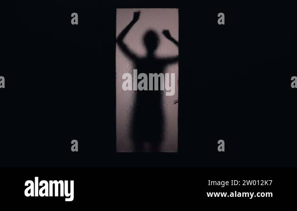 Shadow of scared woman knocking and kicking at glass door, escape from ...