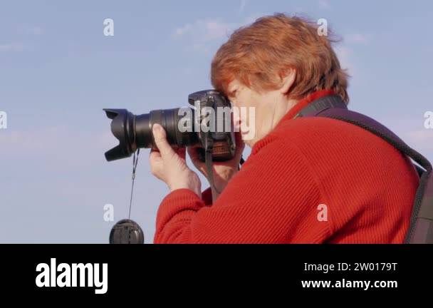 Senior woman taking photo on DSLR camera, focusing. Grandmother's hobby ...