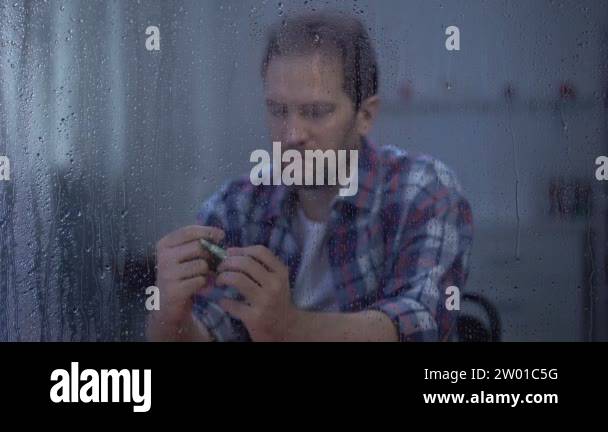 Middle-aged man counting money behind rainy window, poor budget ...