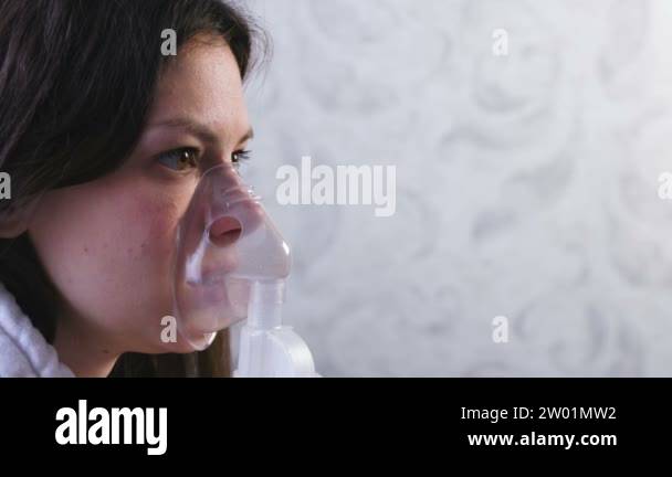 Use nebulizer and inhaler for the treatment. Young woman inhaling ...