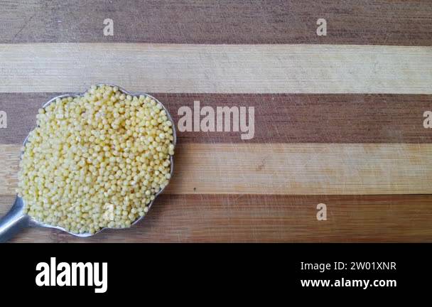 millet grains on a large metal spoon placed on the kitchen Board ...