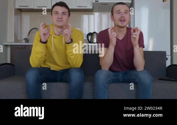 Two superstitious fans pray for the victory of their favorite football team. Two men are ...