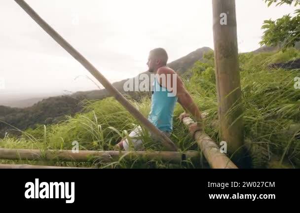 Handsome man doing push up exercise on green hill and tropical ...