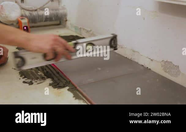 Worker checking level laying tiles on the floor Stock Video Footage - Alamy