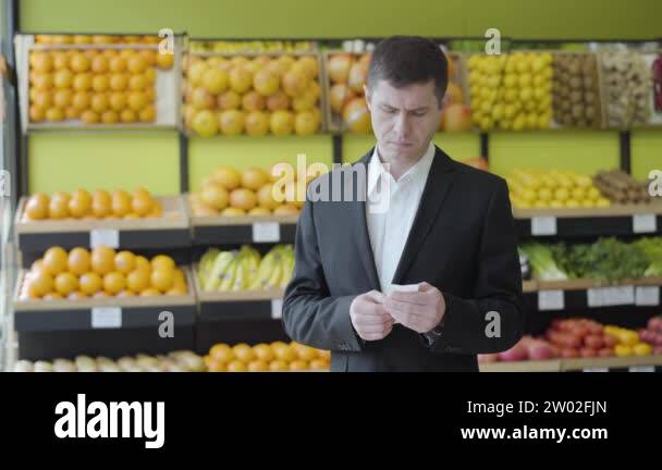 Front view of adult Caucasian man checking bill in grocery with ...