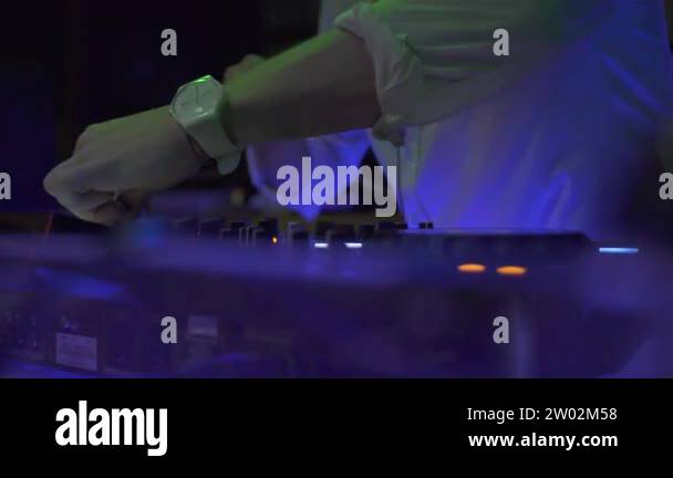 Dj playing music on sound console in colorful light in nightclub. DJ ...