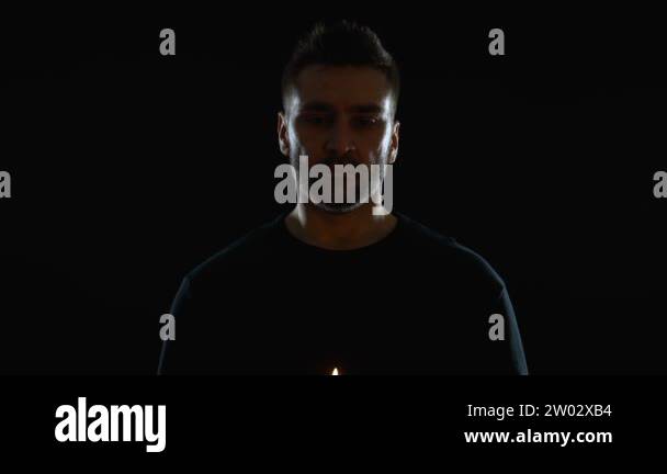 Desperate crying man holding candle on black background, symbol of hope ...