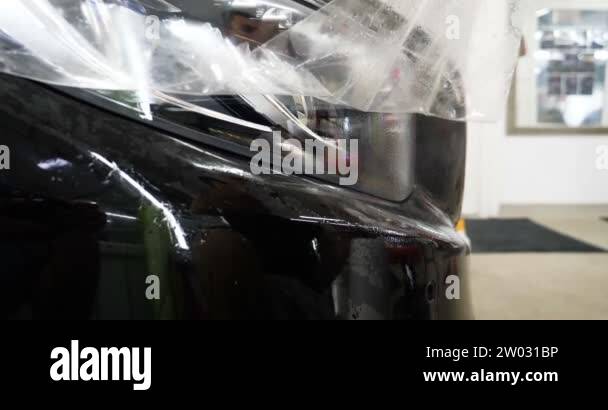 Close up to PPF installation process on a front headlight and hood. PPF ...
