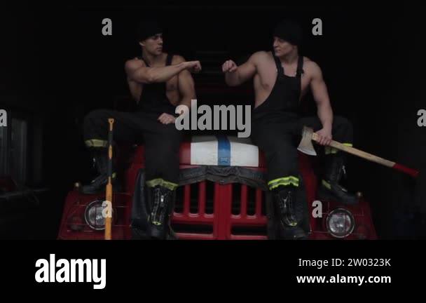 Men do training. Two muscular fireman jump from the hood of a fire ...