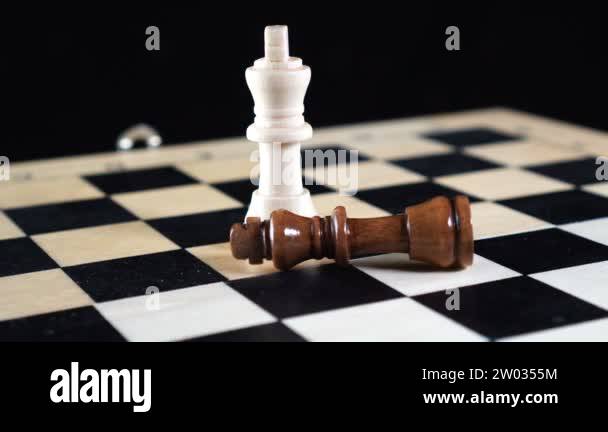 Two chess kings with the vanquished black chess piece lying on its side ...