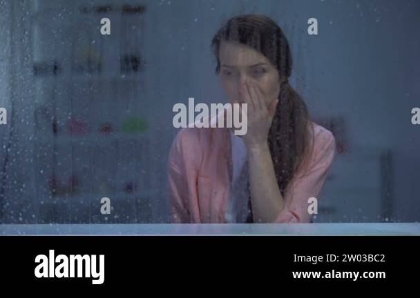 Crying middle-aged woman looking through rainy window, life and health ...