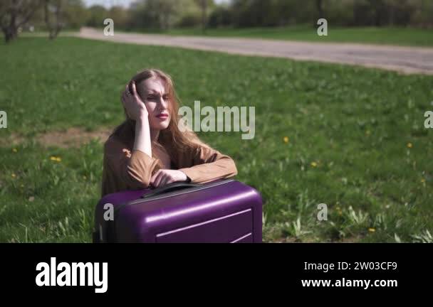 Sad traveler missed her flight and bus - Sitting on her luggage ...