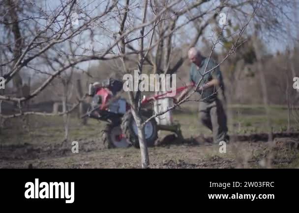 Senior Caucasian man furrowing fertile Ukrainian soil in the early ...