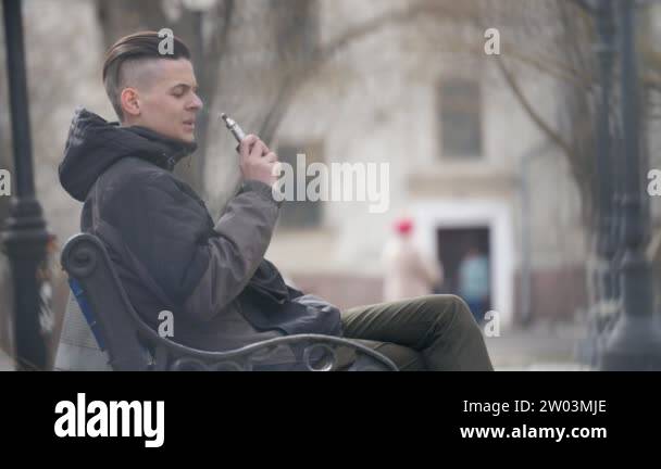 Street brunet man smoking e-cigarette and breathing out fume rolls in ...