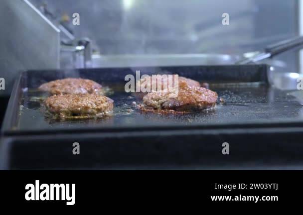 Cooking a hamburger, patty or steak. On a hot stove, a cook fries meat ...