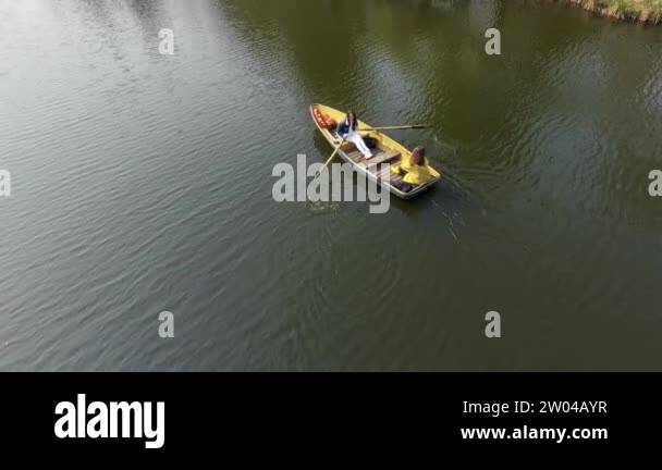 Two young pretty girls are boating in the small boat in the middle of ...