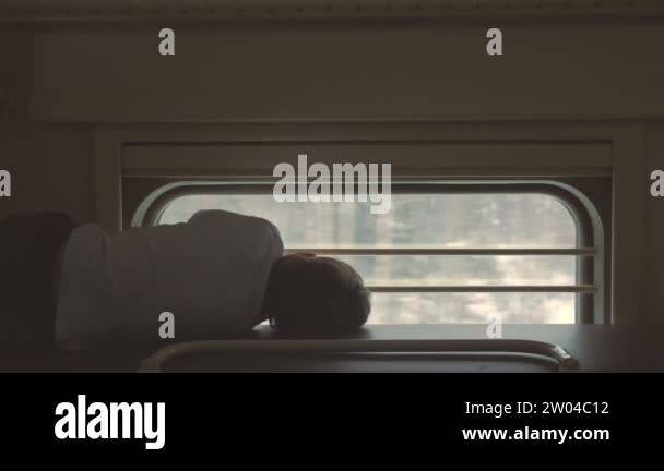 Boy on the train lying on the top shelf in a second-class carriage and ...