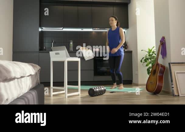 Woman jumping and doing fitness aerobic exercises at home in kitchen ...