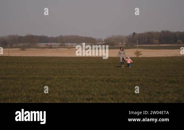 young mother with a child walk by hand from afar across the field Stock ...