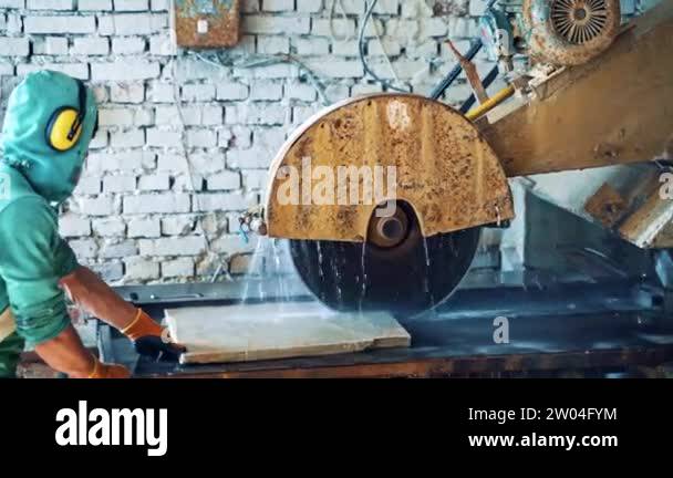 Man worker is putting stone slab into the CNC machine in factory ...