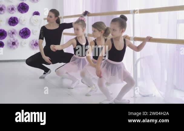 Concentrated girls are learning basic ballet positions in dancing ...