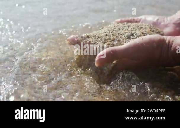 Two hands keeping sand on the Alanya shore in summer in slow motion ...