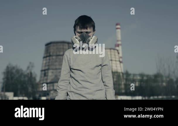 Young boy Wearing respirator using mobile phone Against Factory ...