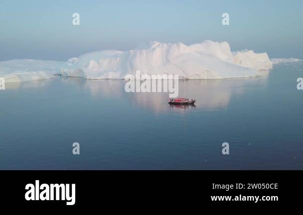 A small boat among icebergs. Sailboat cruising among floating icebergs ...
