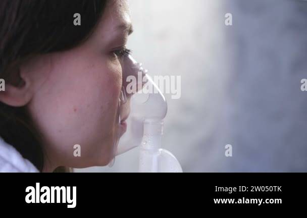 Use nebulizer and inhaler for the treatment. Young woman inhaling ...
