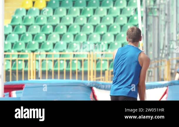 Pole vault - a young man prepares and starts to run up holding a pole ...
