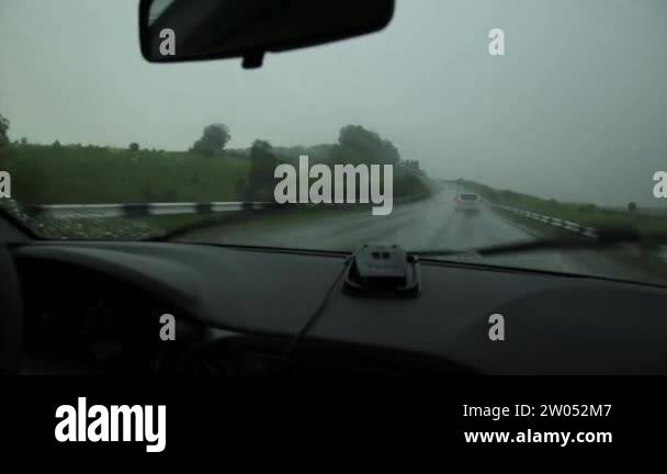 Driving in a nasty rainy day, dashboard and steering wheel with drivers ...