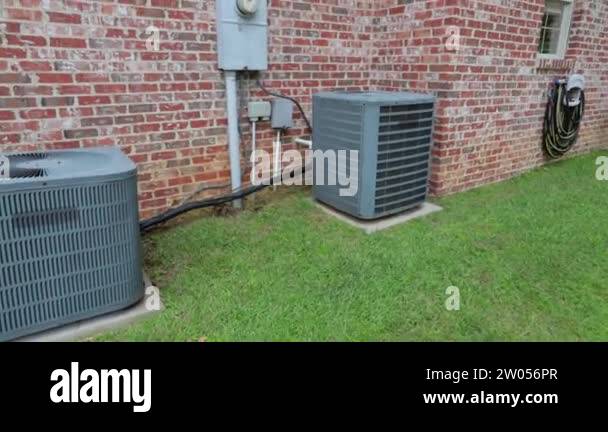 Camera moves around to view two air conditioner units next to brick ...