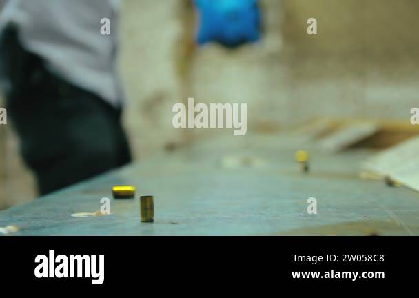 Empty pistol bullet shells dropping and impacting wooden table in a ...