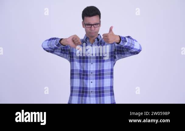 Confused young Indian hipster man giving thumbs up and thumbs down ...