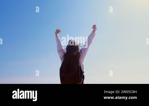 Girl winner in victory pose with raising hands on sky background back ...