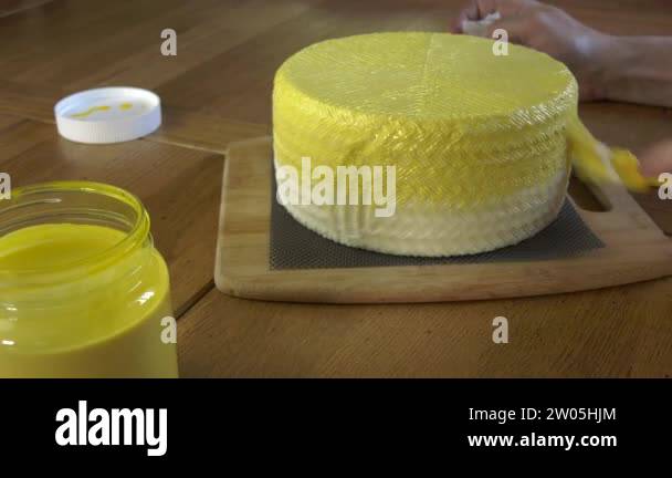 The cheesemaker covers the white cheese head with a yellow protective ...