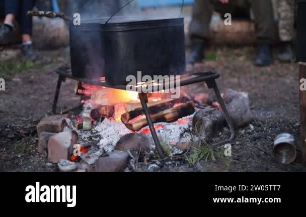 People heating up water in the metal buckets using a bonfire. Throw ...