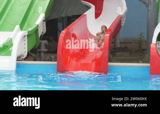 Slender brunette girl in bikini riding in a red aqua tube in Alanya in slow motion Funny view of ...