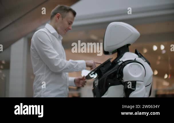 A man stands with a robot bot and asks him questions and asks for help ...
