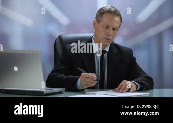 Attentive company boss reading and signing documents at office table ...