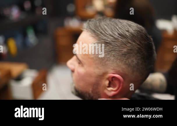 Hairdresser woman adds final touches to a haircut and taking off salon ...