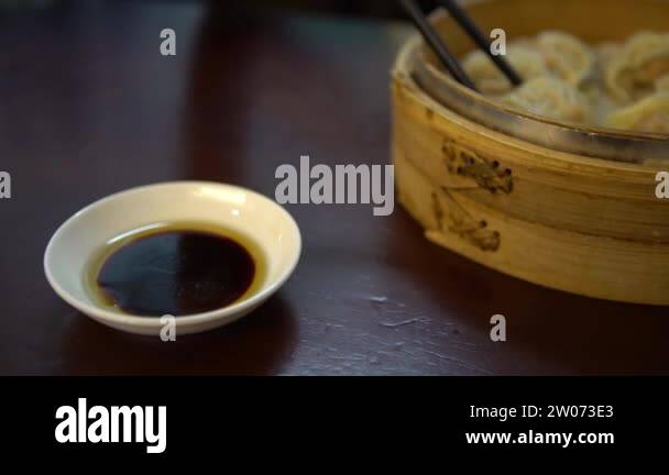 4K Dipping dumpling into soy sauce in a restaurant. Eat the hot ...