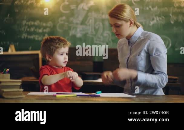 Little cute boy with young teacher studying in classroom and makes ...