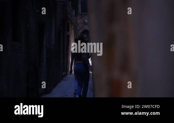 Two young scared women walking on the narrow mysterious street. A light ...