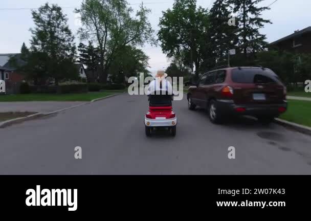 Disabled person driving a motorized mobility scooter in cityscape for ...