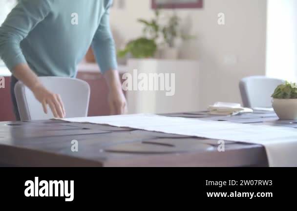 Two people setting the table up in living room putting dishes for meal ...