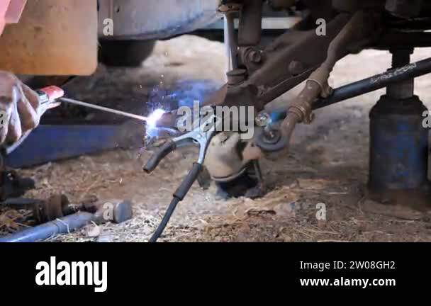 Mechanic using welder to welding the truck to repair wishbone control ...