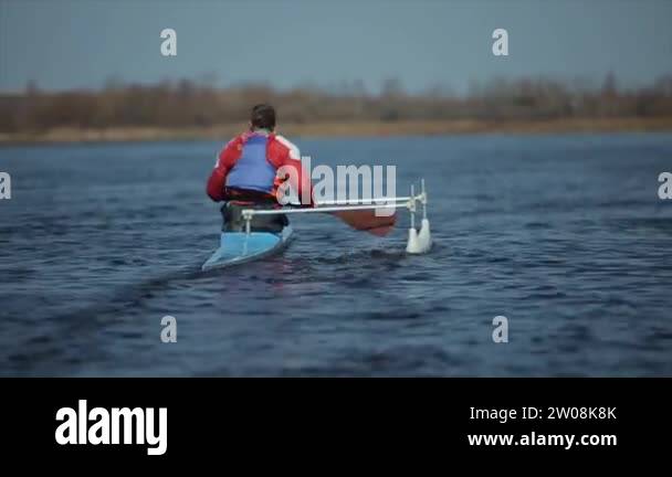 Rear view of Athlete rowing on the river in a canoe. Rowing, canoeing ...